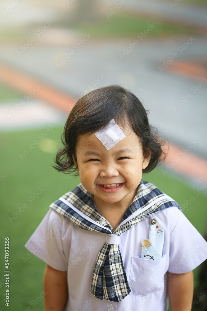 An Asian little girl who wearing a kindergarten uniform and has a wound ...