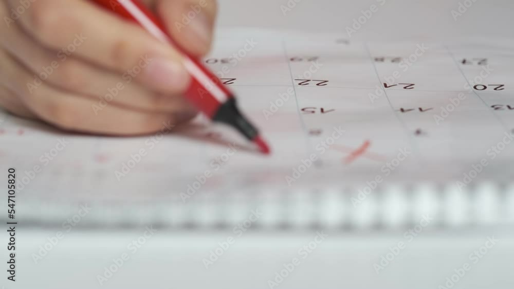 Blurred calendar page. Close-up female hand cross out days in calendar ...