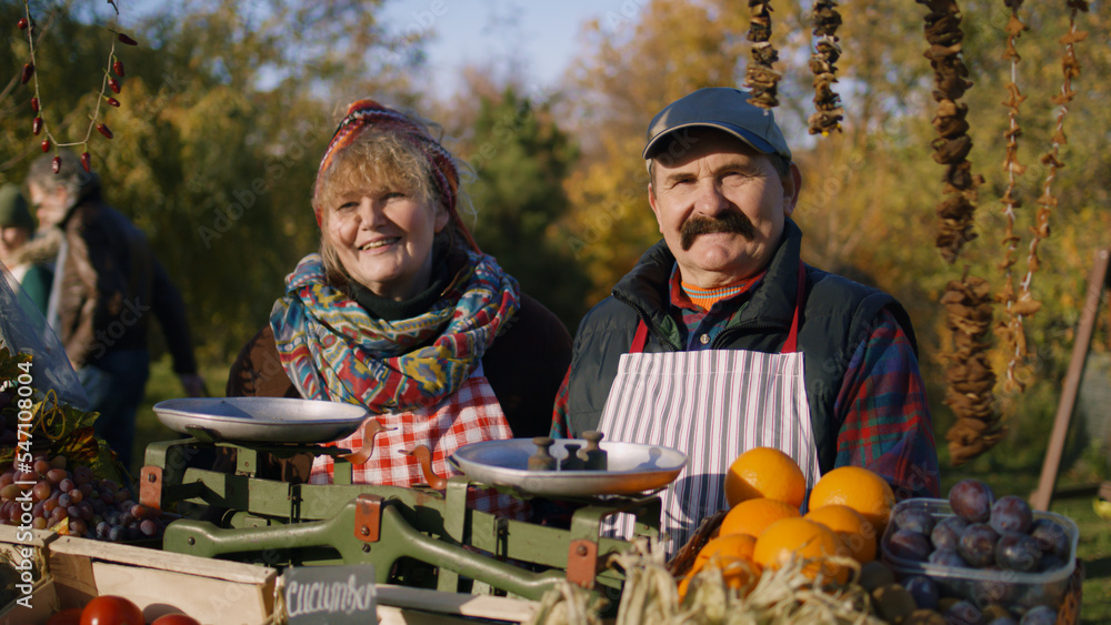 Happy elderly couple of farmers standing near fresh fruits and ...