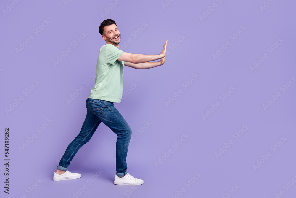 Full size photo of handsome young man pushing empty space wall cheerful ...