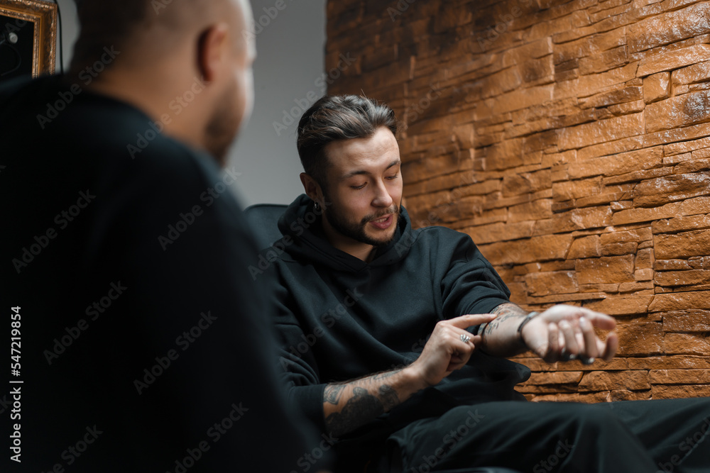 Interior of a tattoo studio - a man shows his tattoos to a master ...
