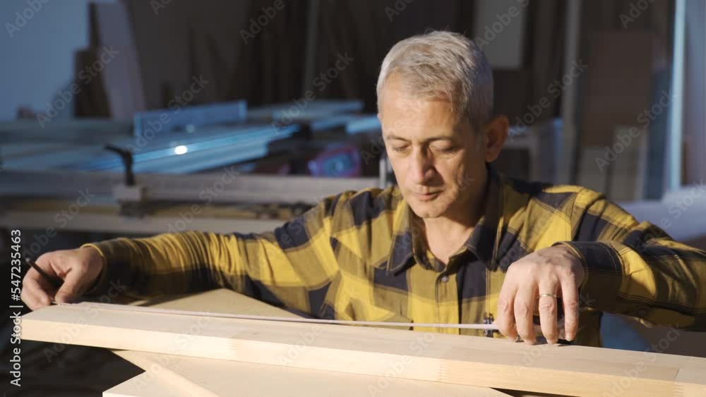 Carpenter man measuring wooden boards with meter. The male carpenter ...