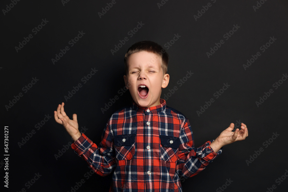 Angry little boy screaming on black background. Aggressive behavior ...