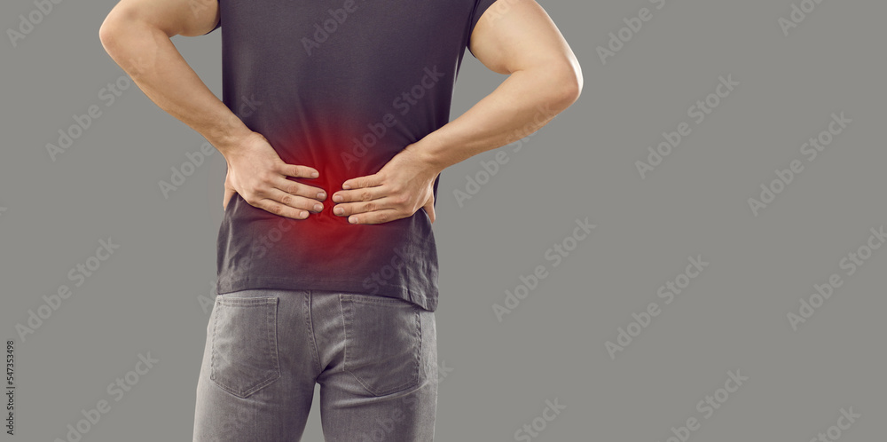 Man suffering from pain and touching his lower back. Backside view from ...