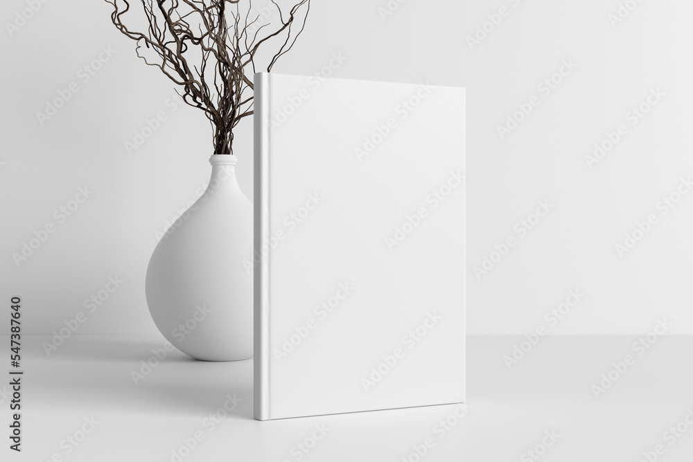 Vertical book cover mock up standing on a white desk with white wall ...
