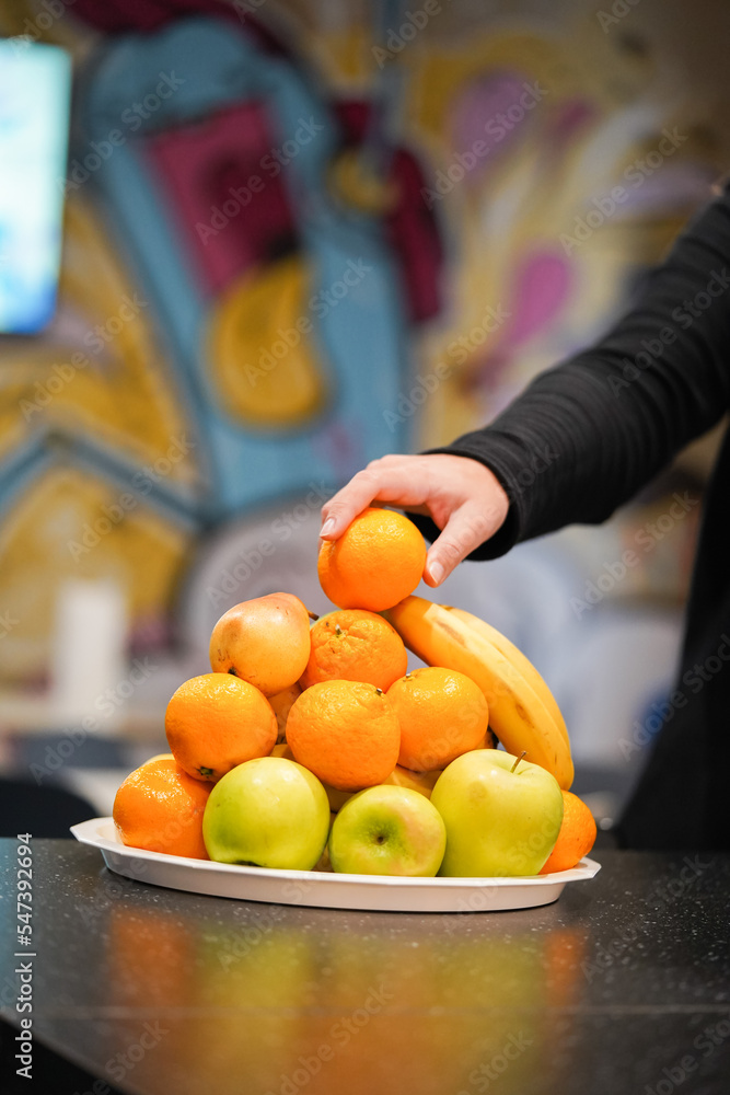 Hand of a girl taking the fruit off the plate in a modern designed room ...