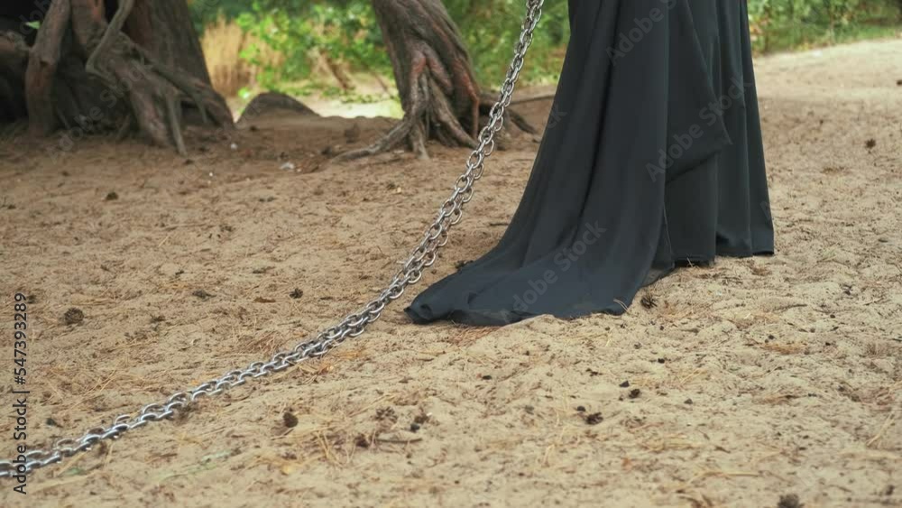 fantasy medieval goth woman holding pulling iron chains stretches across ground. Girl witch ...