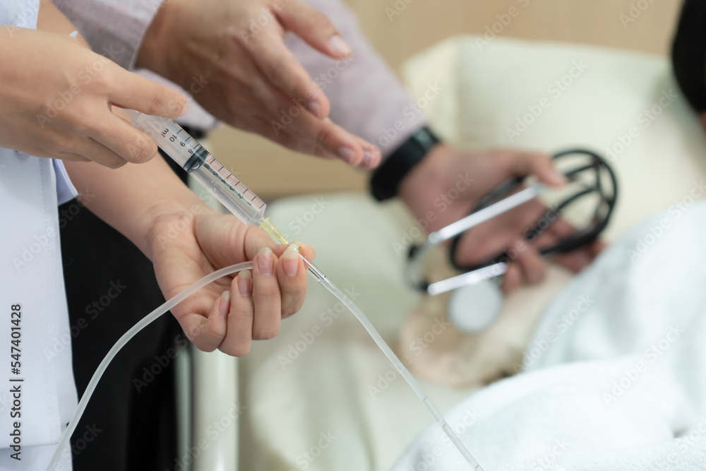 Doctor and nurse inject medicine, dosage into IV tube providing medical ...