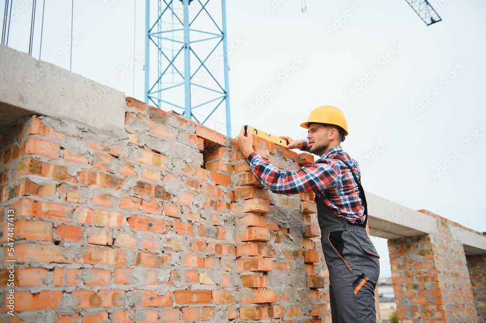 Installing brick wall. Construction worker in uniform and safety ...
