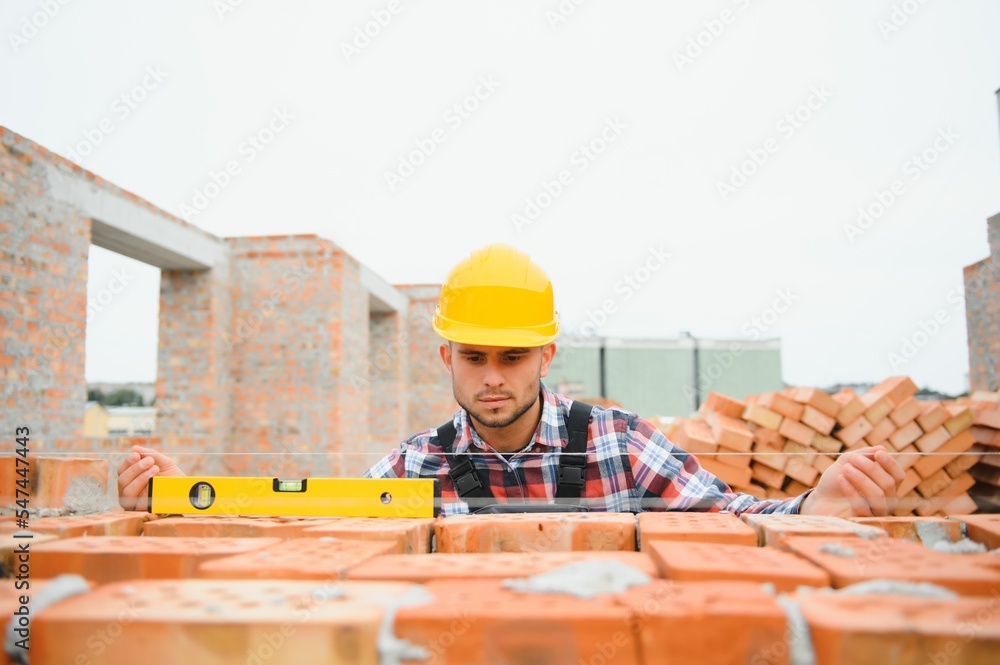 Busy with brick wall. Construction worker in uniform and safety ...