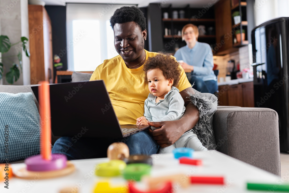 Father spends time with a cute daughter watching a laptop computer with ...