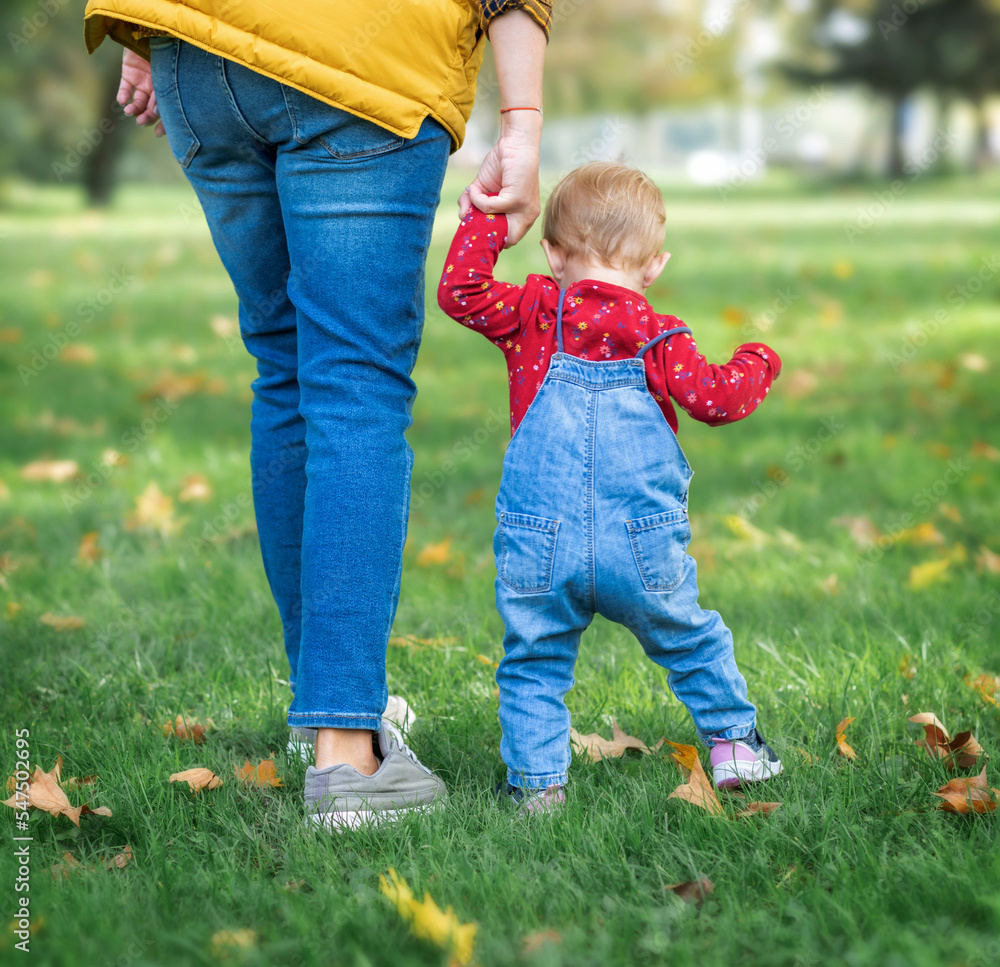 Young mother woman teaching her little child to walk. Little baby first ...