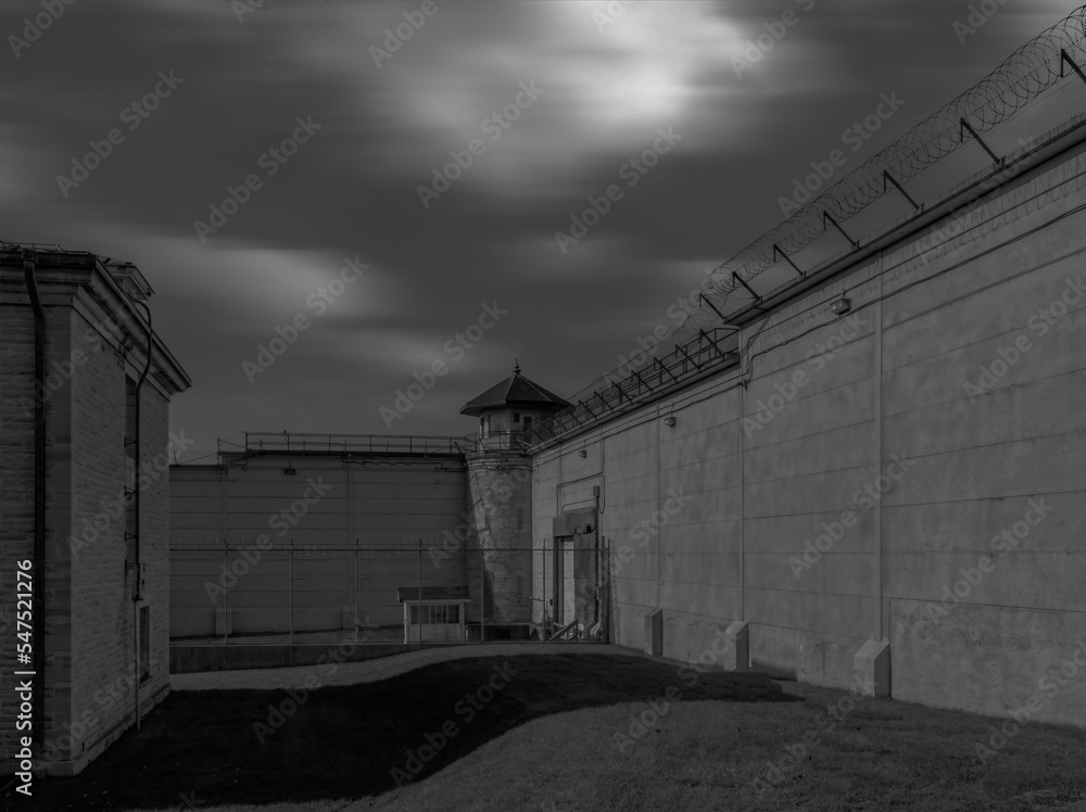 Outdoors in a penitentiary yard with two high limestone walls topped ...