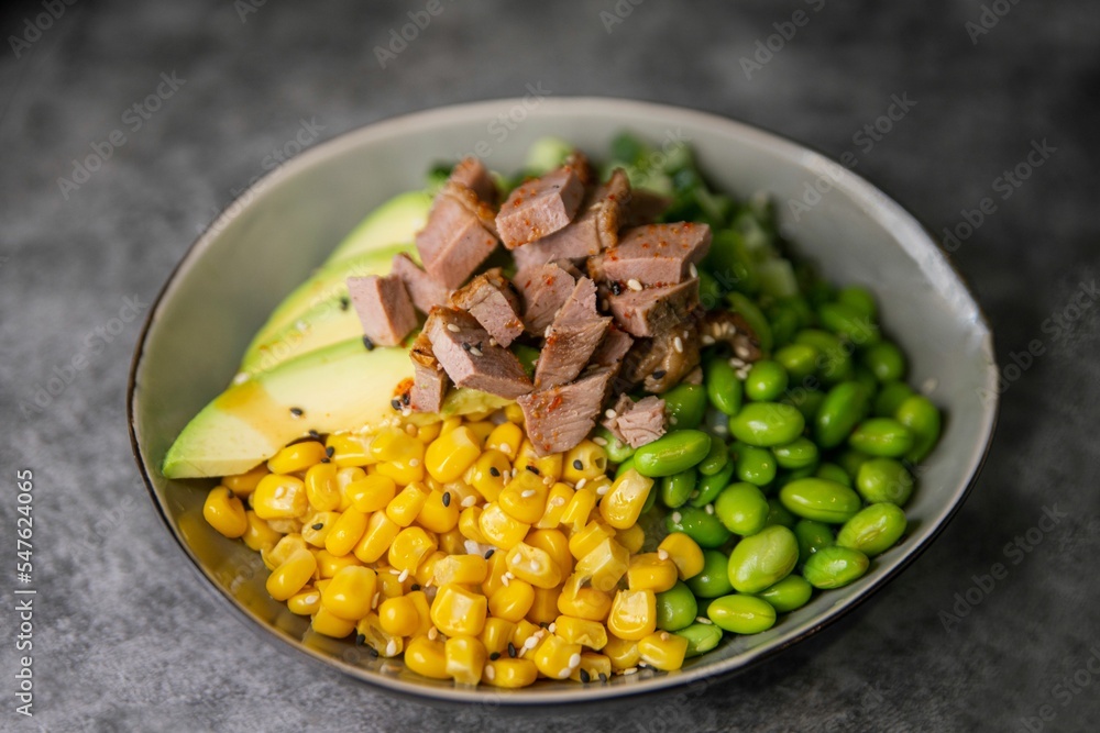 Poke bowl with meat, avocado, edamame beans, cucumber, corn and sesame ...