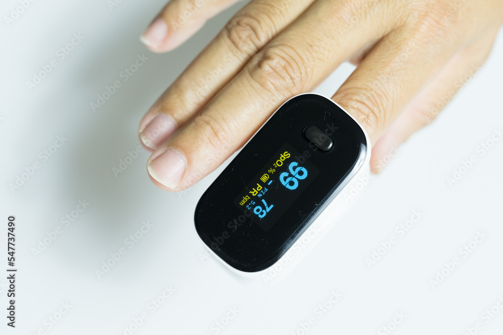 Woman resting at home using pulse oximeter to monitor blood oxygen ...