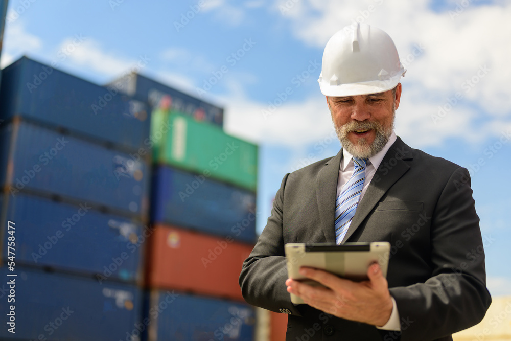 Smart businessman in white helmet and black suit holding tablet ...