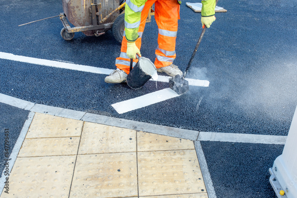 Road workers applying hot melt traffic resistant paint for white ...