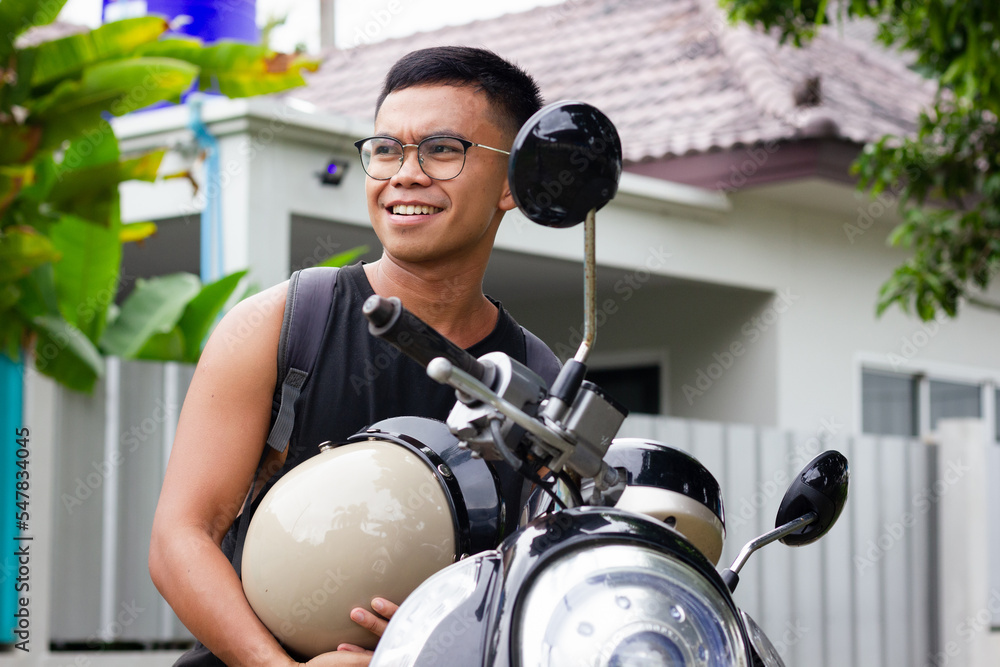 Smiling Filipino man with eyeglasses sitting on scooter holding vintage ...