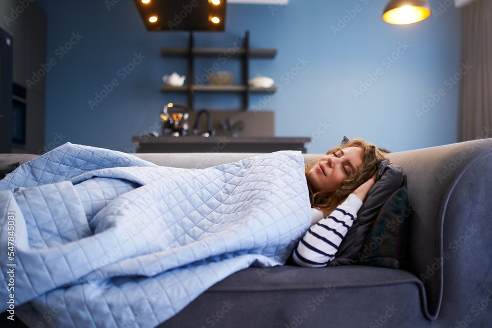 Girl sleeps on cozy sofa in living room at siesta time under a warm ...