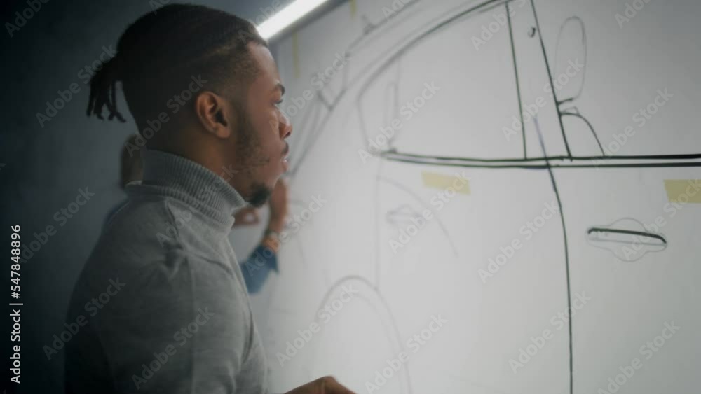 Two diverse automotive male designers creating sketch with duct tap on ...
