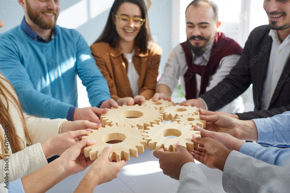 Young business people stacking wooden gears cog in office closeup ...