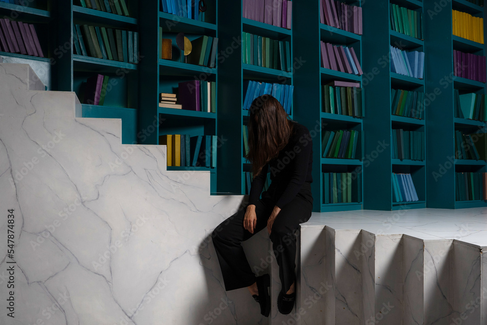 A sad student is sitting on a strange staircase against the background ...
