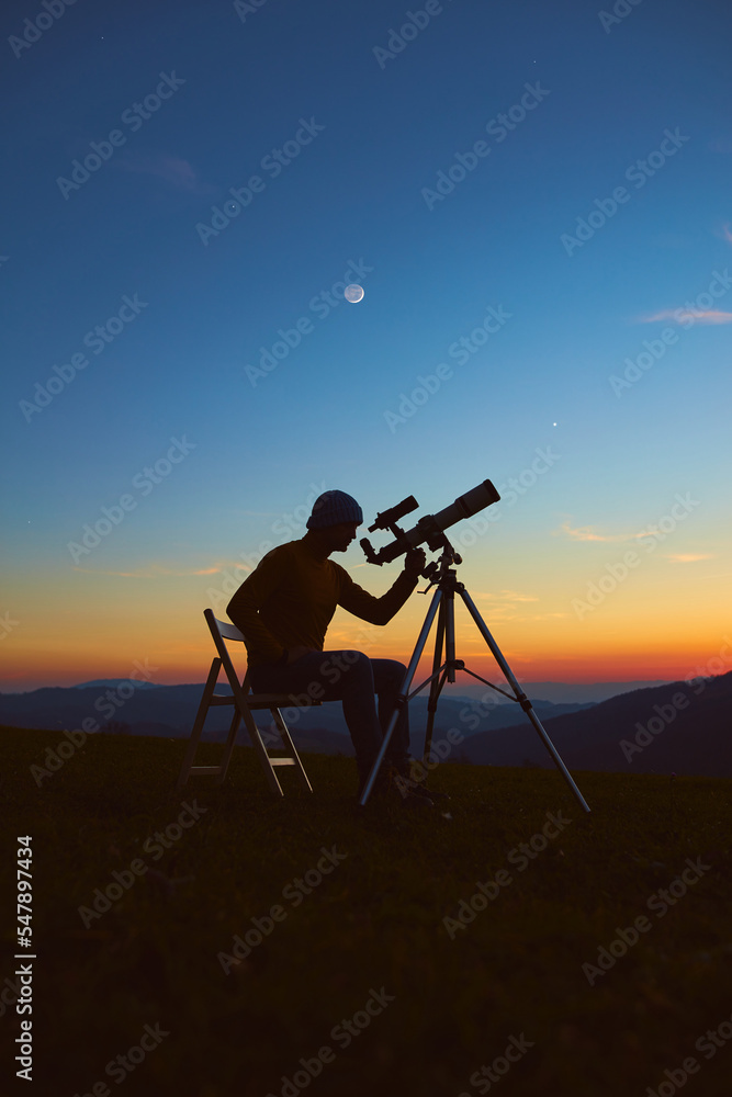 Man with astronomy telescope looking at the night sky, stars, planets ...