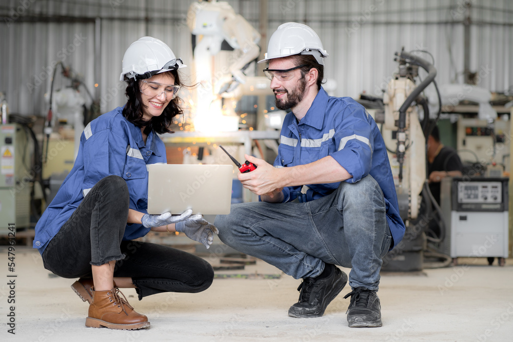 Industrial engineers use robotic welding machine and automation software control system working ...