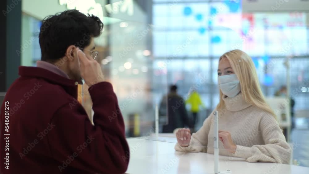 Pretty female staff wearing protective face mask giving mask to male ...