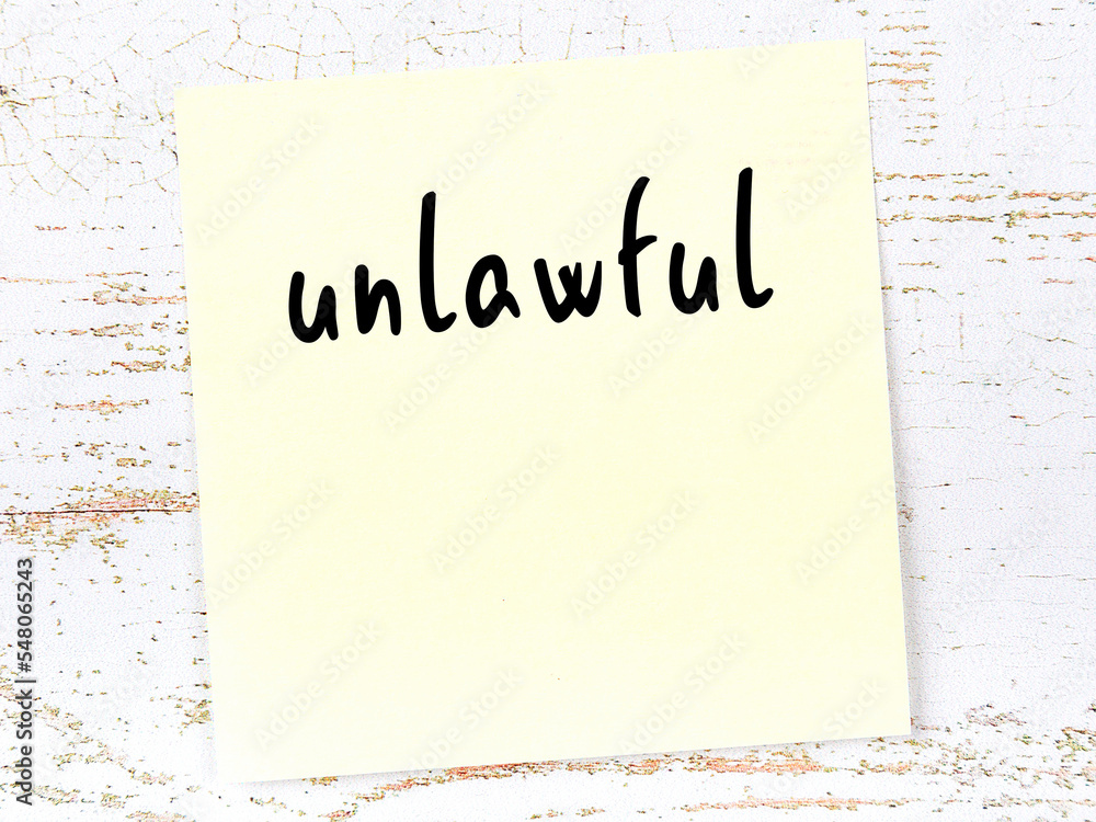 Yellow sticky note on wooden wall with handwritten word unlawful Stock ...