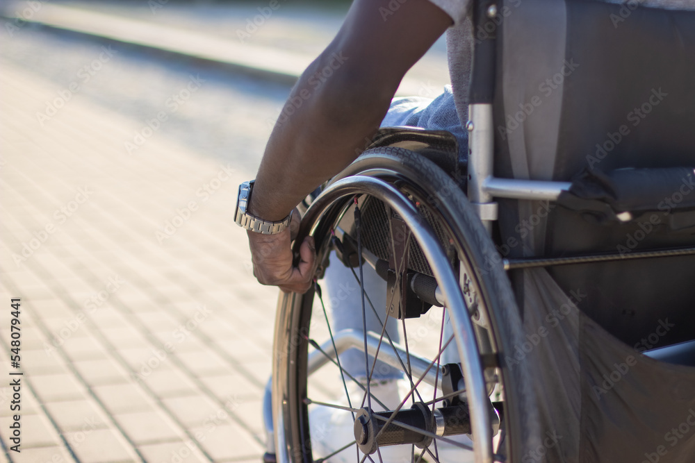 Close-up of muscular male arm rolling wheelchair wheel in habitual ...
