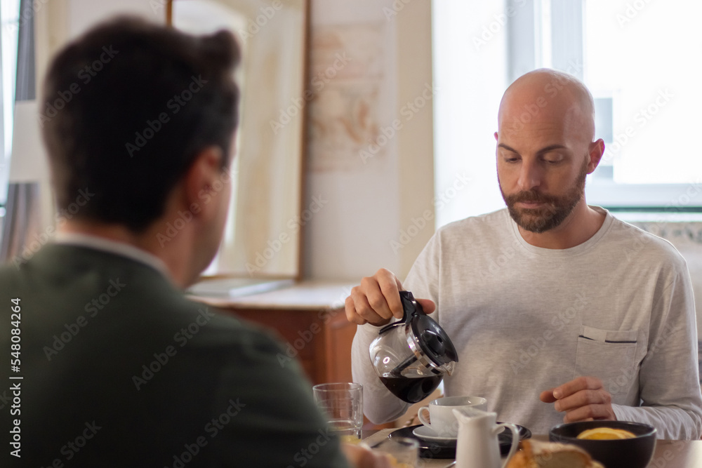 Homosexual men sitting at kitchen table and having breakfast. Handsome ...
