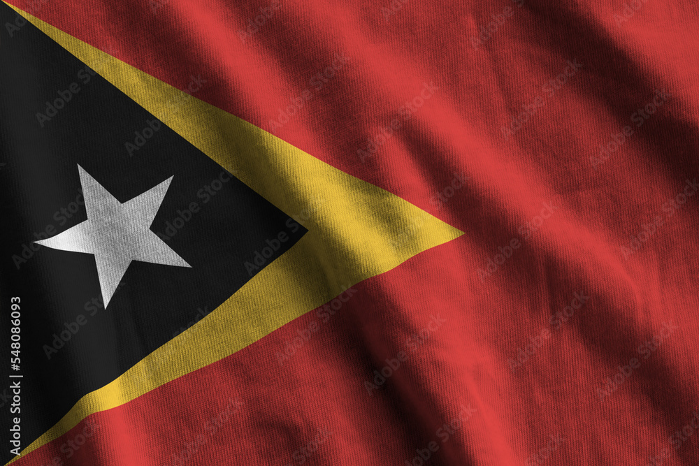 Timor Leste flag with big folds waving close up under the studio light ...