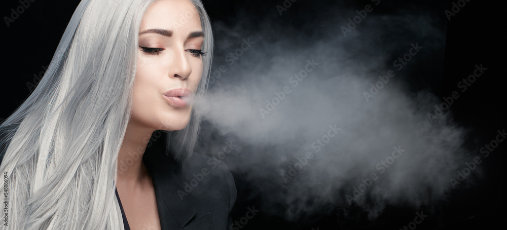 Vaping concept. Gorgeous vaper woman blowing a big steam cloud in a ...