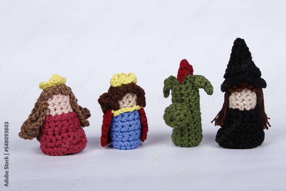 Crocheted king, queen, dragon and witch finger puppets on a white ...
