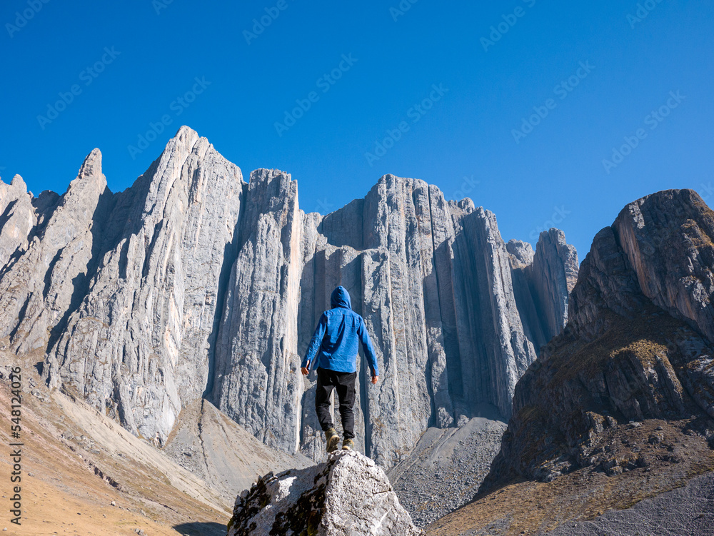 Hombre parado sobre una roca o piedra, con una casaca o chamarra color ...