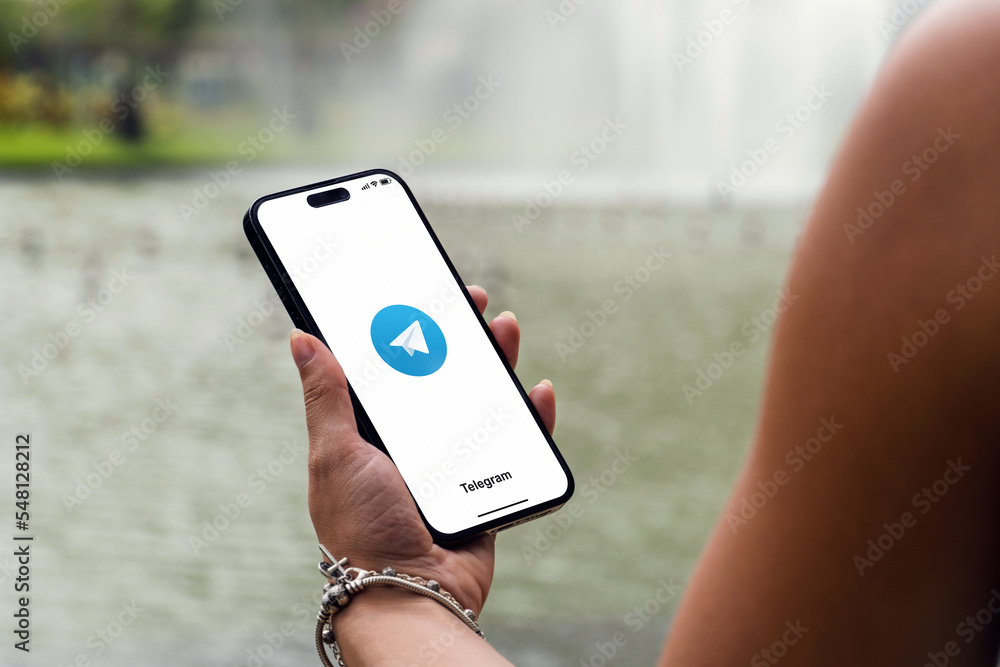 Girl in the park holding a smartphone iPhone 14 Pro with Telegram app ...