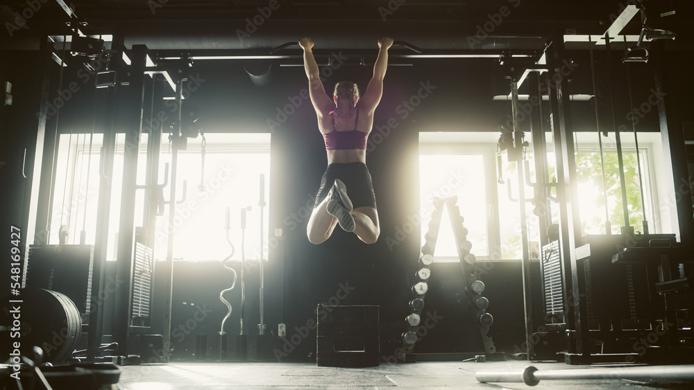 Wide, Back View Shot: Muscular Woman hanging from Gym Equipment to ...