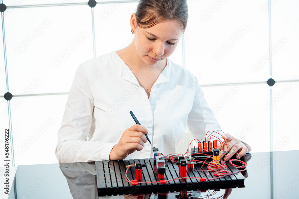schoolgirl student studying electrical circuits at a physics lesson ...