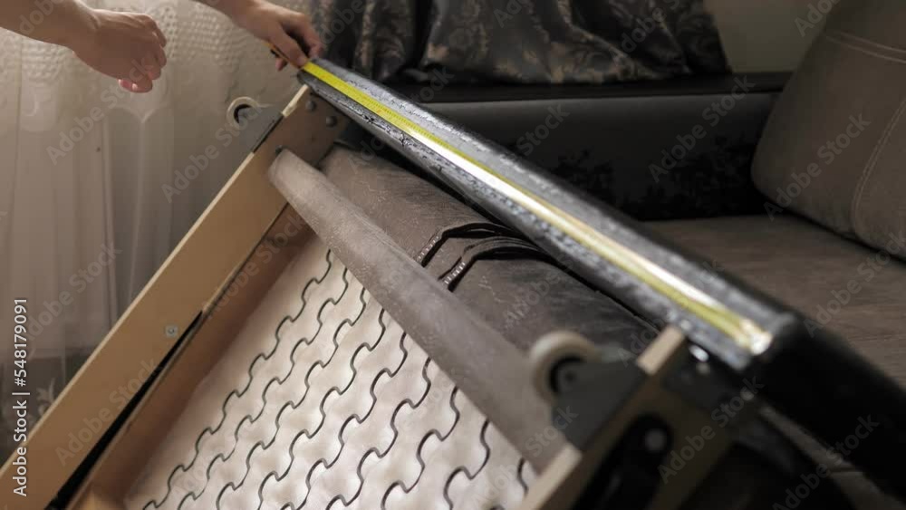 Young girl measures the length with a tape measure of a sofa on the ...