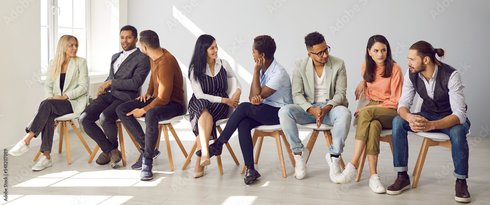 Web narrow banner of multiracial young people sit on chairs in row talk ...