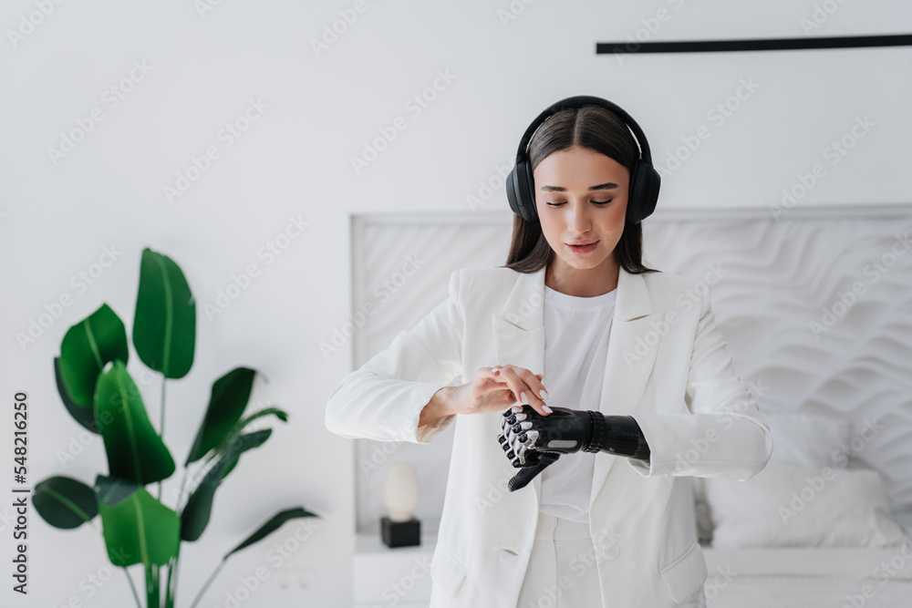 Attractive brunette girl in white suit uses touchpad on artificial hand ...
