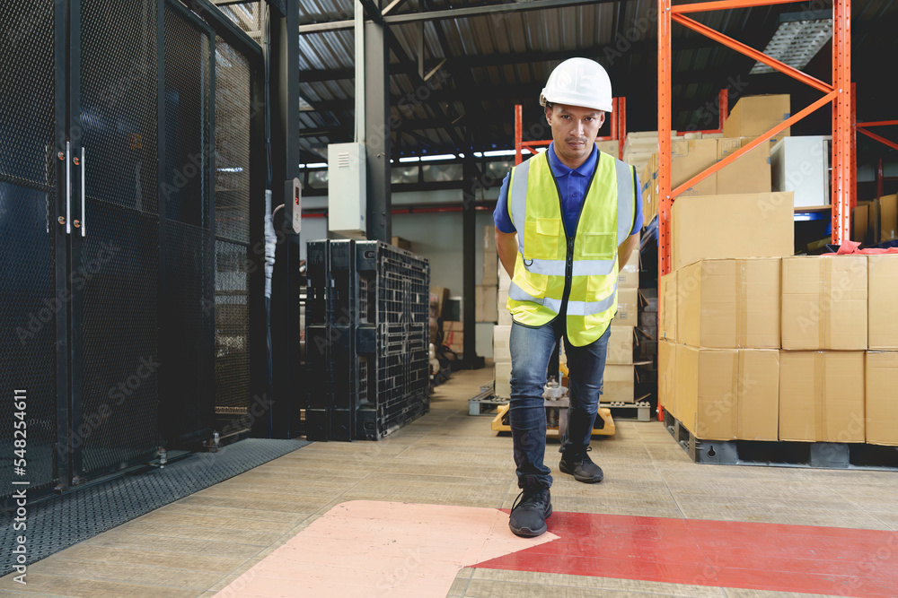 Asian male warehouse worker pulling a pallet truck. Worker working with ...