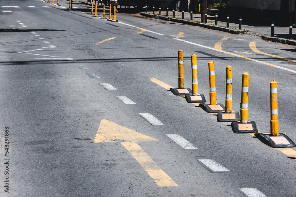 Yellow and white bollards on the street to split lanes and an arrow as ...