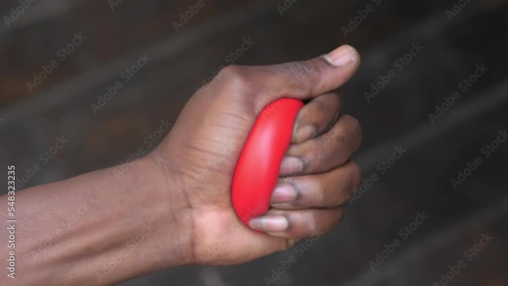An african man hand shows red stress ball and starts squeezing and ...
