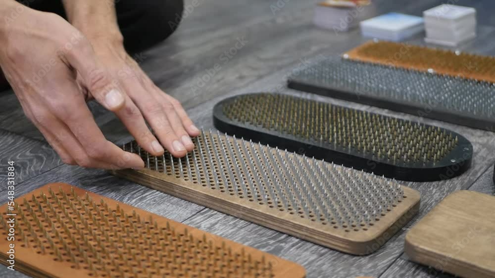 The hands of a male practitioner of standing on nails lay out various ...
