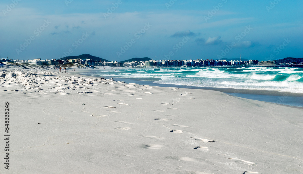 Orla da Praia das Dunas, com algumas dunas de areia, céu azul e a ...
