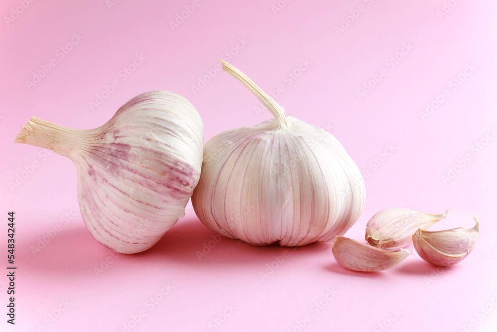 Fresh white unpeeled head bulb of garlic and garlic cloves on pink ...