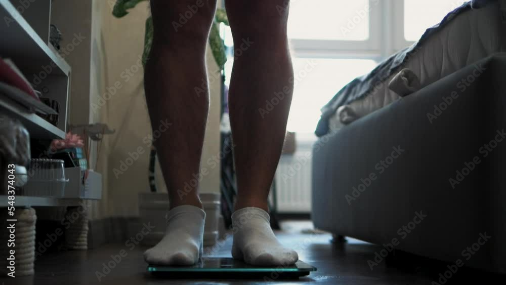 Men's feet stand on floor scales. A person is weighed on a scale to ...