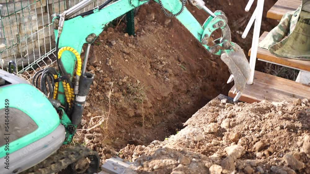 Mini excavator digs a trench to lay pipes. Close up of an excavator ...